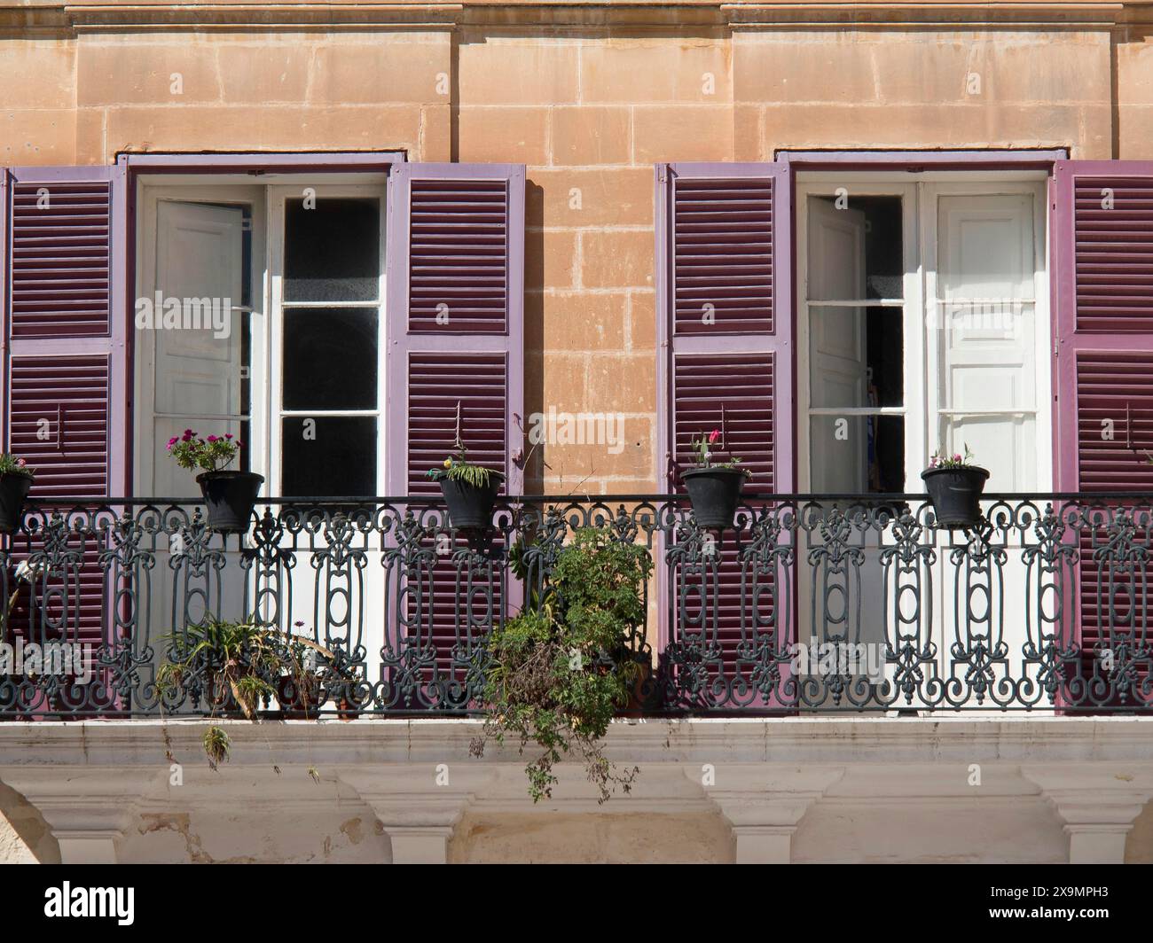 A mediterranean balcony with purple shutters and potted plants in front ...