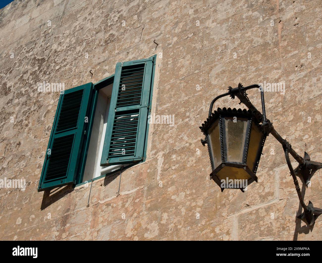 Open window with green shutters and old lantern on a stone wall, the ...
