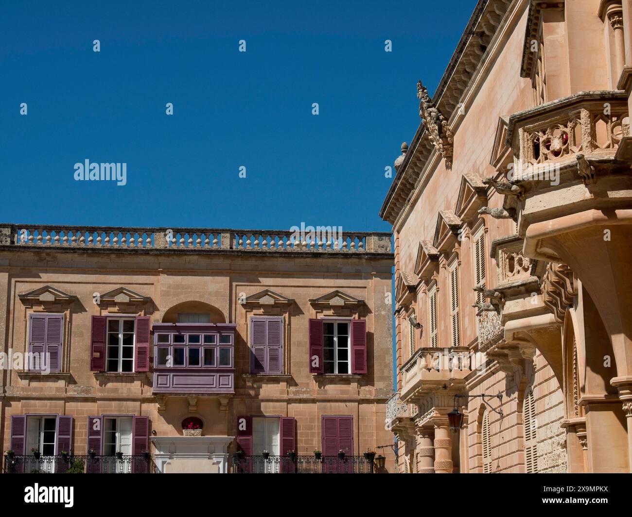 Two buildings with historic stone walls and shutters under a clear sky ...