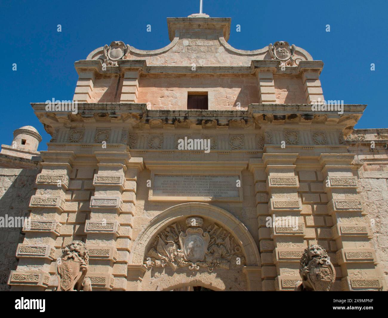 A historic Tor tor with lion sculptures and coats of arms under a blue ...