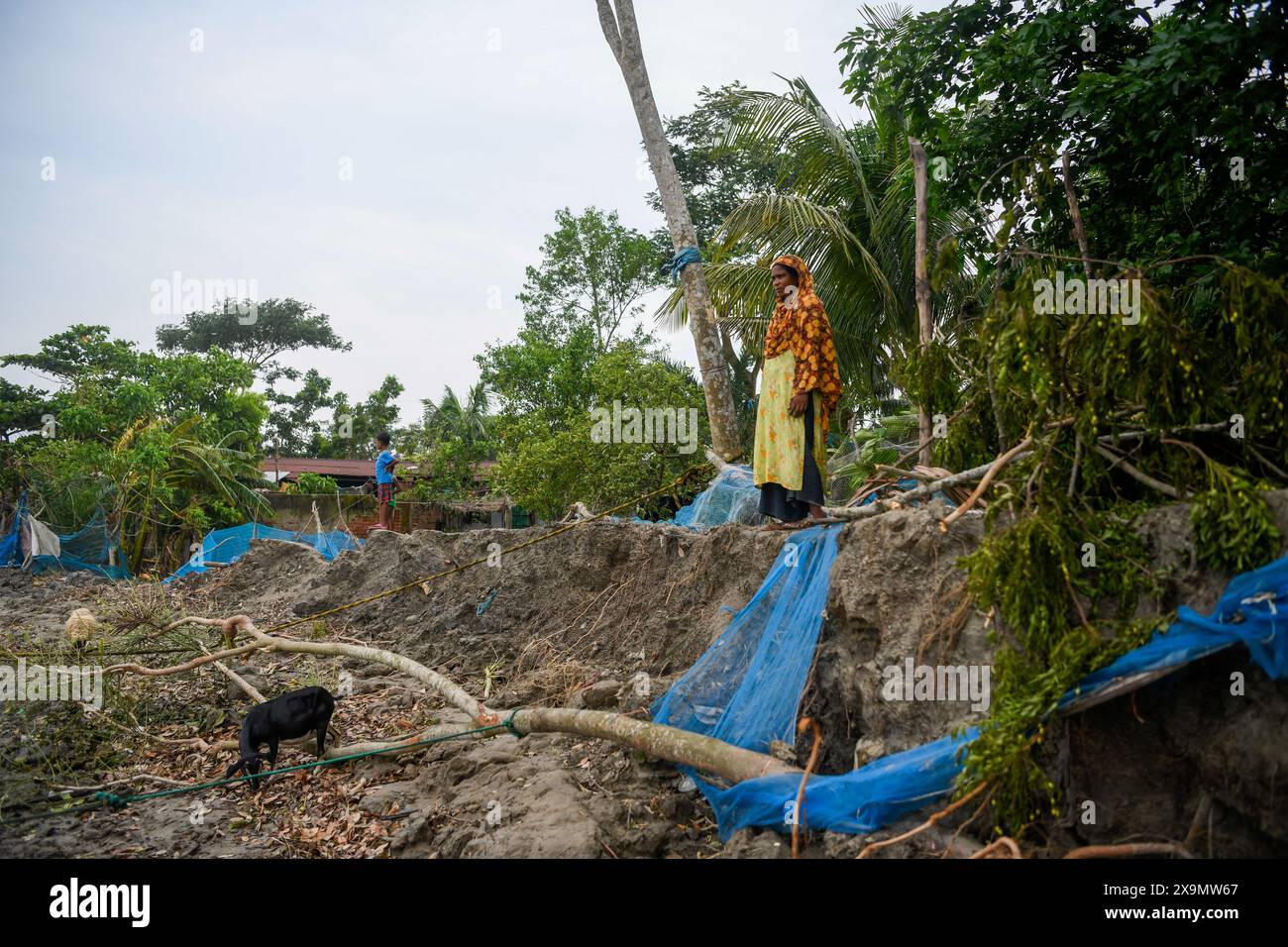 A woman stands at a damaged home during the aftermath in Mongla ...