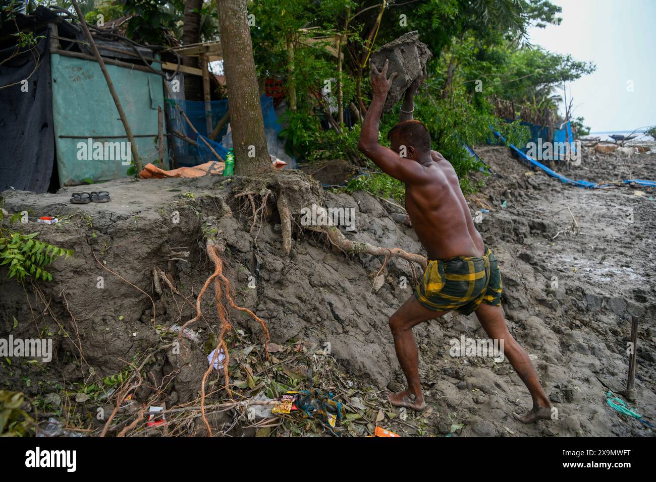 A man is repairing the dam in front of his house during the aftermath ...