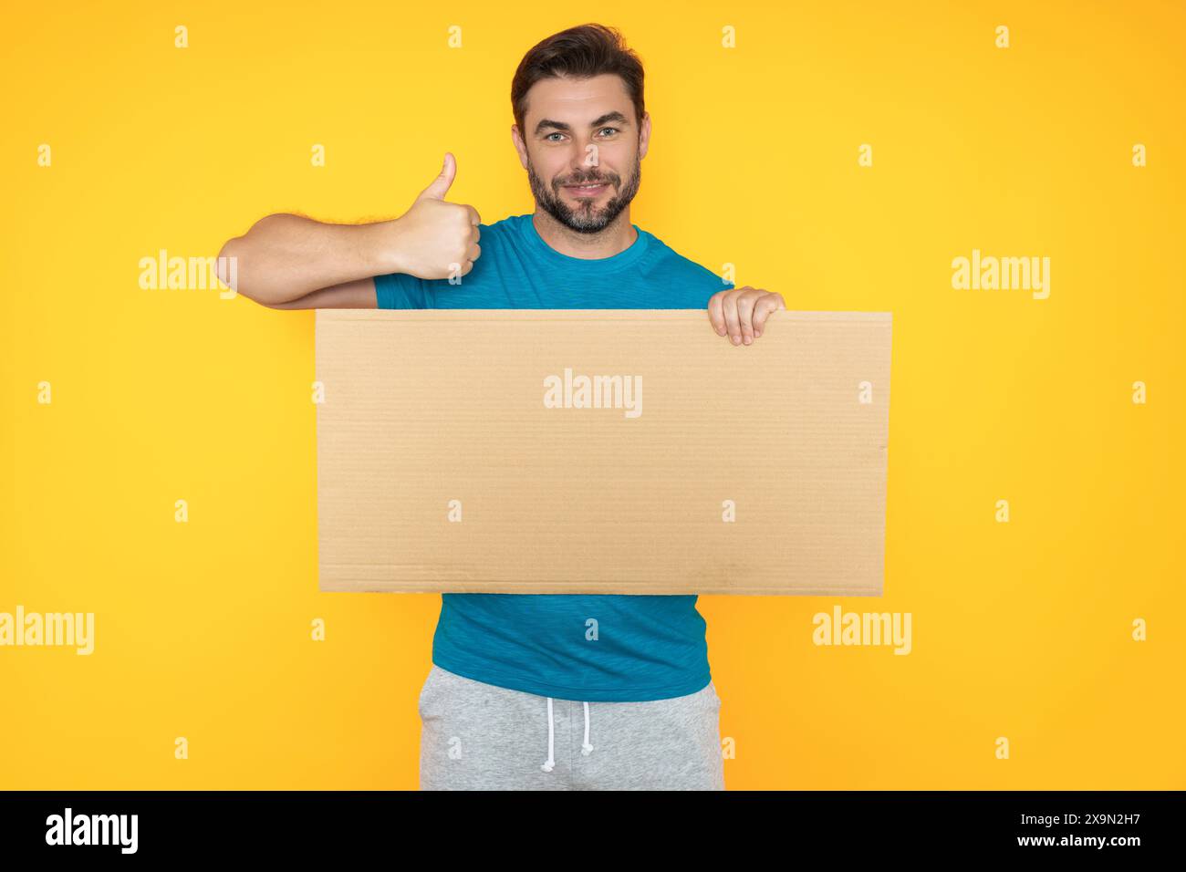 Man with thumb up and blank banner ad, on studio background. Portrait ...