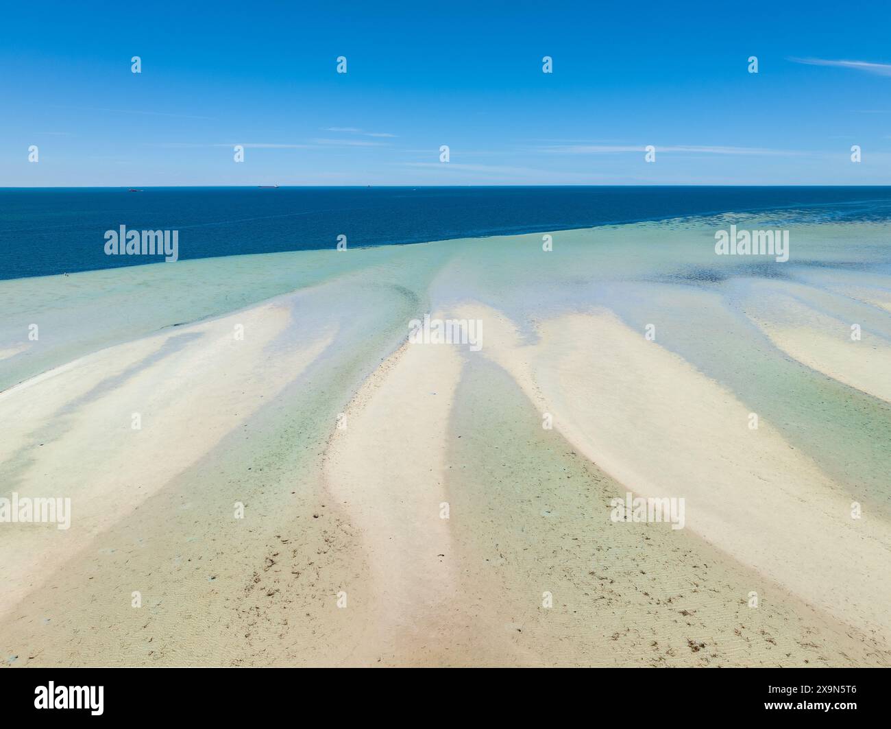 Aerial view of ripples and pools of water along a white sandy beach at ...