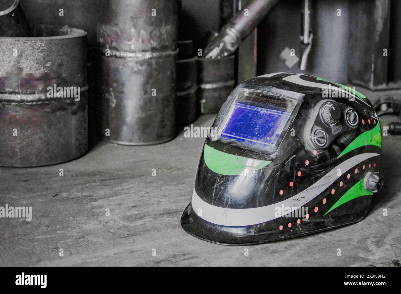 A professional welding helmet rests on a tabletop amidst industrial ...