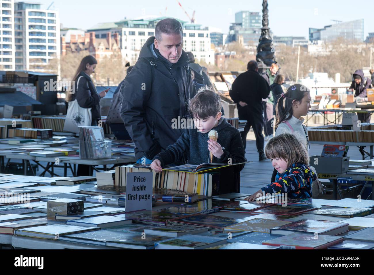 A father & two children browse through the books at open air Southbank ...
