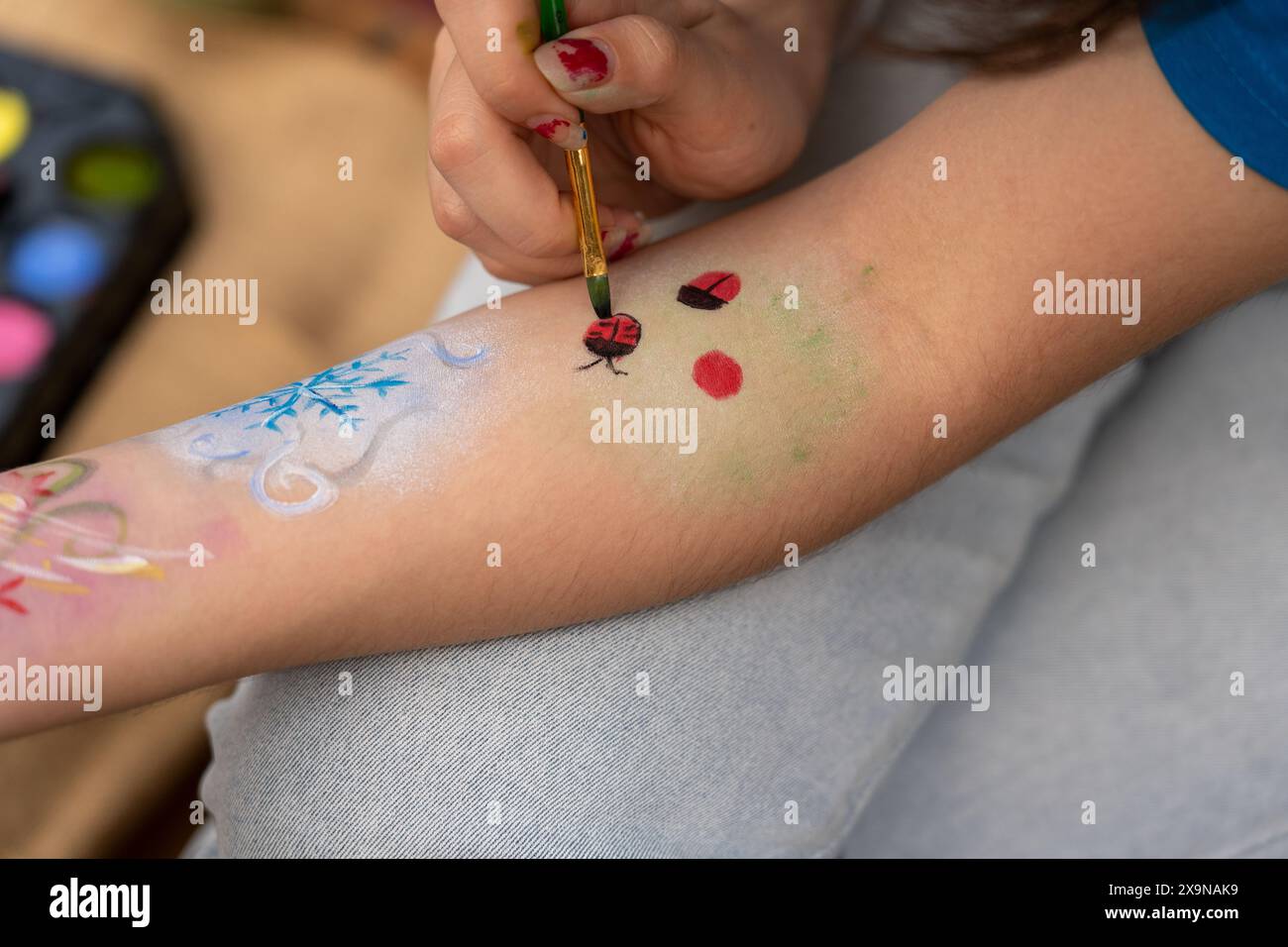 Face painting at a carnival, painting on a childs arm Stock Photo - Alamy