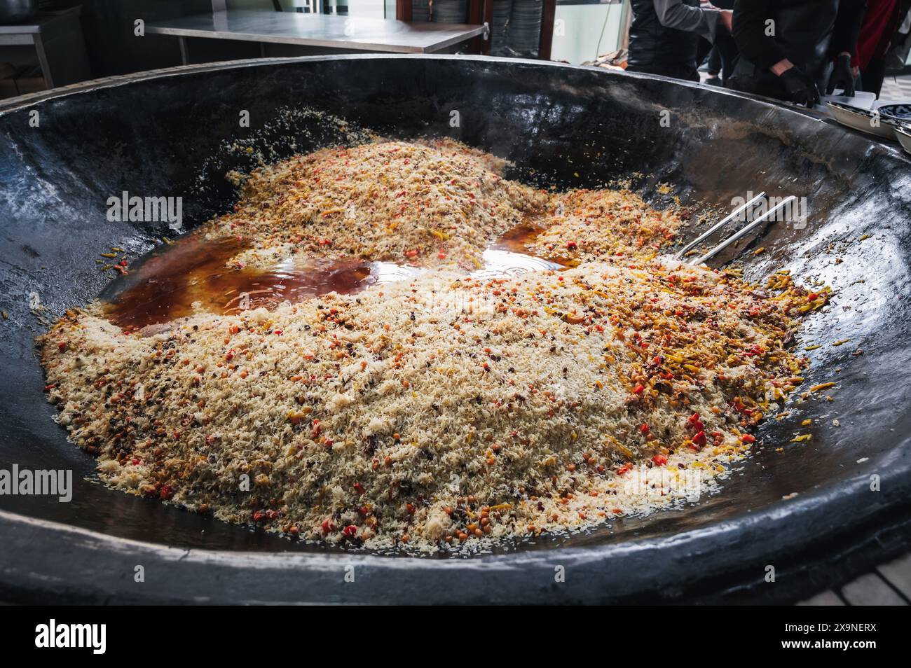 oriental dish of Uzbek cuisine is pilaf in a huge cauldron in the ...
