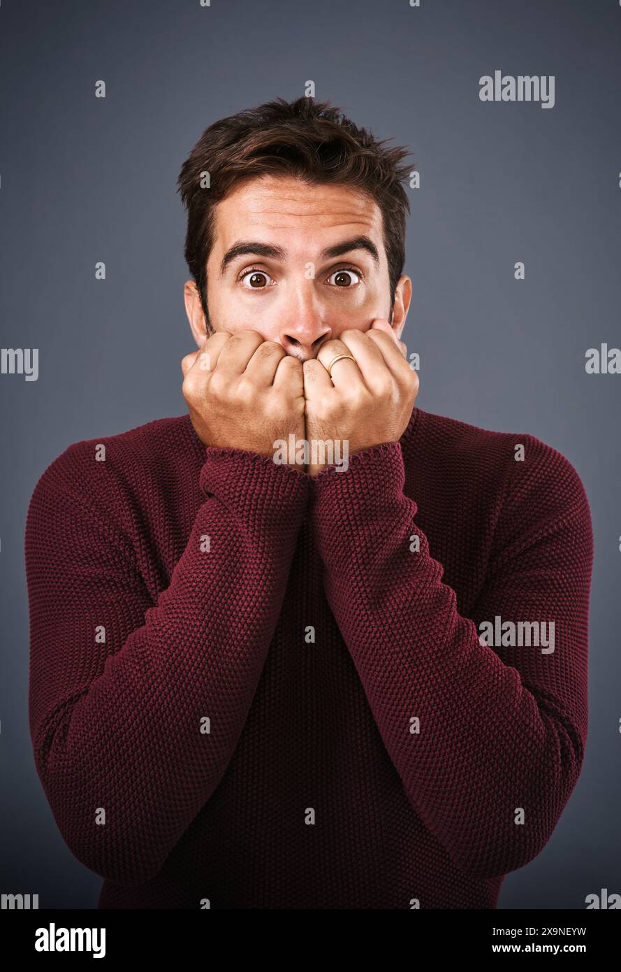 Portrait, scared and phobia of man in studio, anxiety and biting of ...