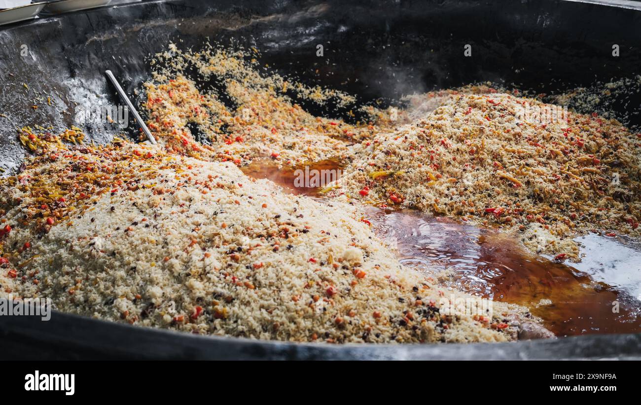traditional asian Uzbek pilaf in a huge cauldron in kitchen at the ...