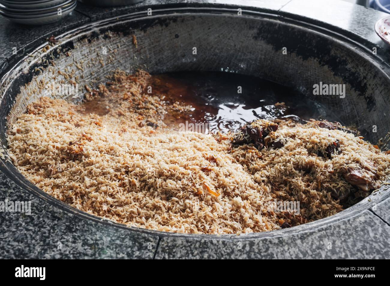 cooking traditional uzbek dish rice pilaf with meat lamb in a large ...