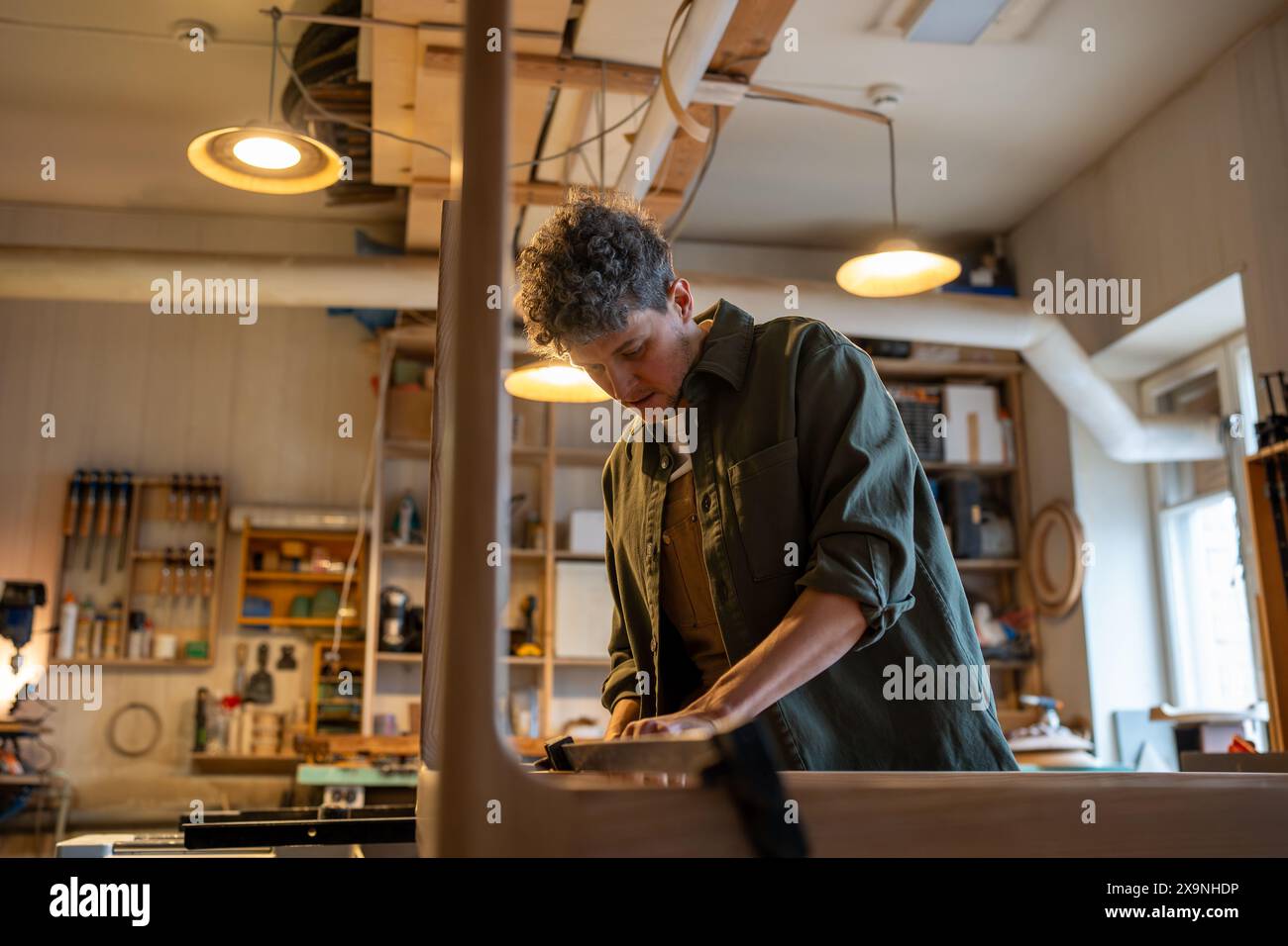 Concentrated carpenter working on making a table, using clamping ...