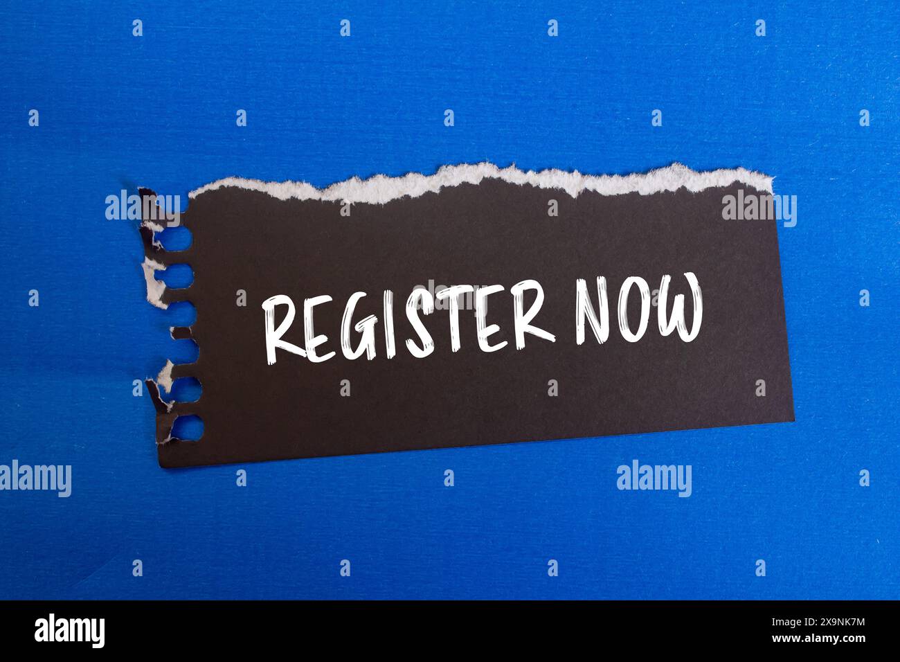 Register now message written on ripped black paper piece with blue ...