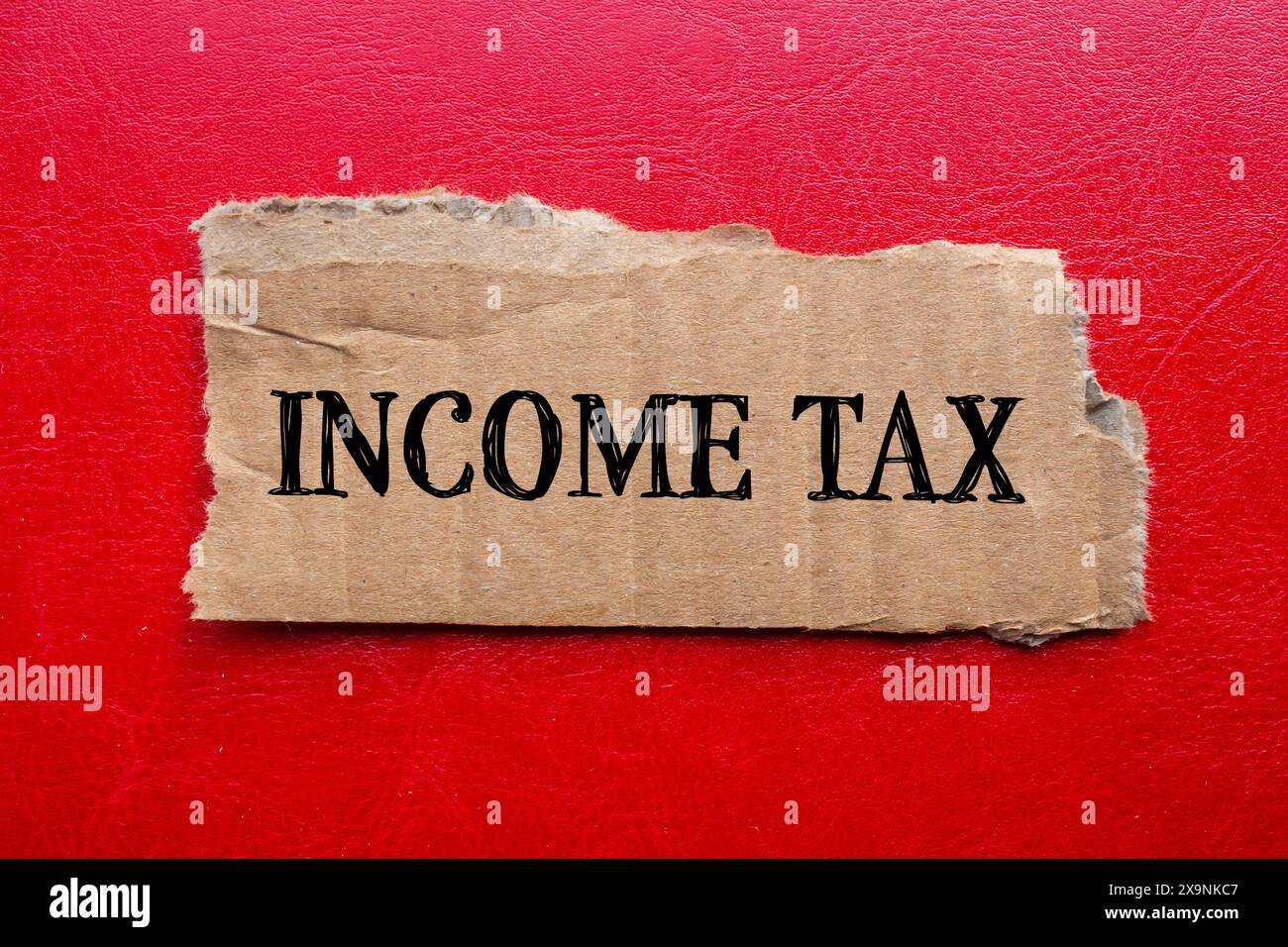 Income tax words written on ripped cardboard paper piece with red ...