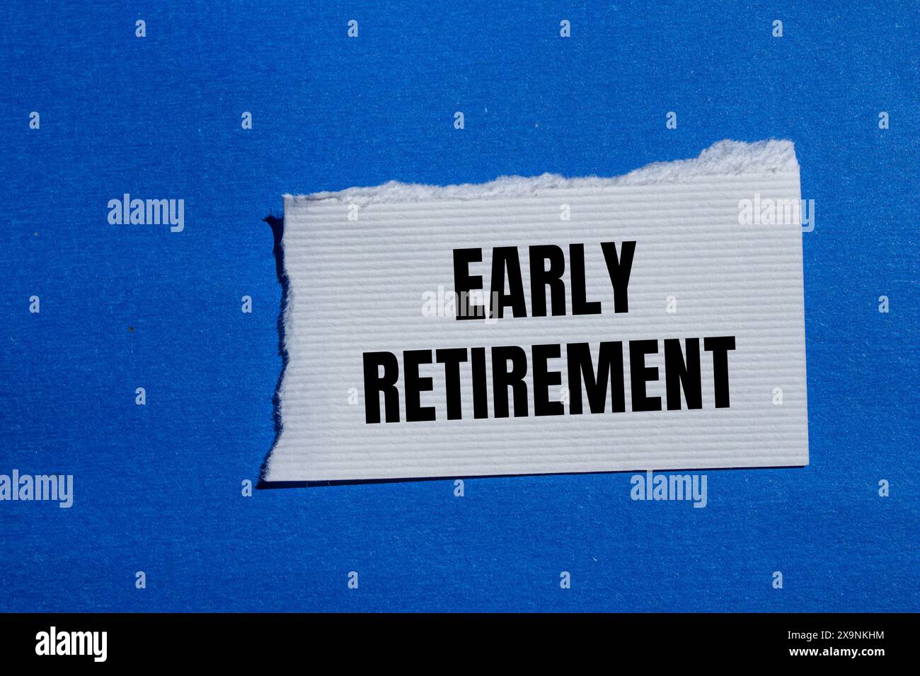 Early retirement words written on ripped white paper piece with blue ...