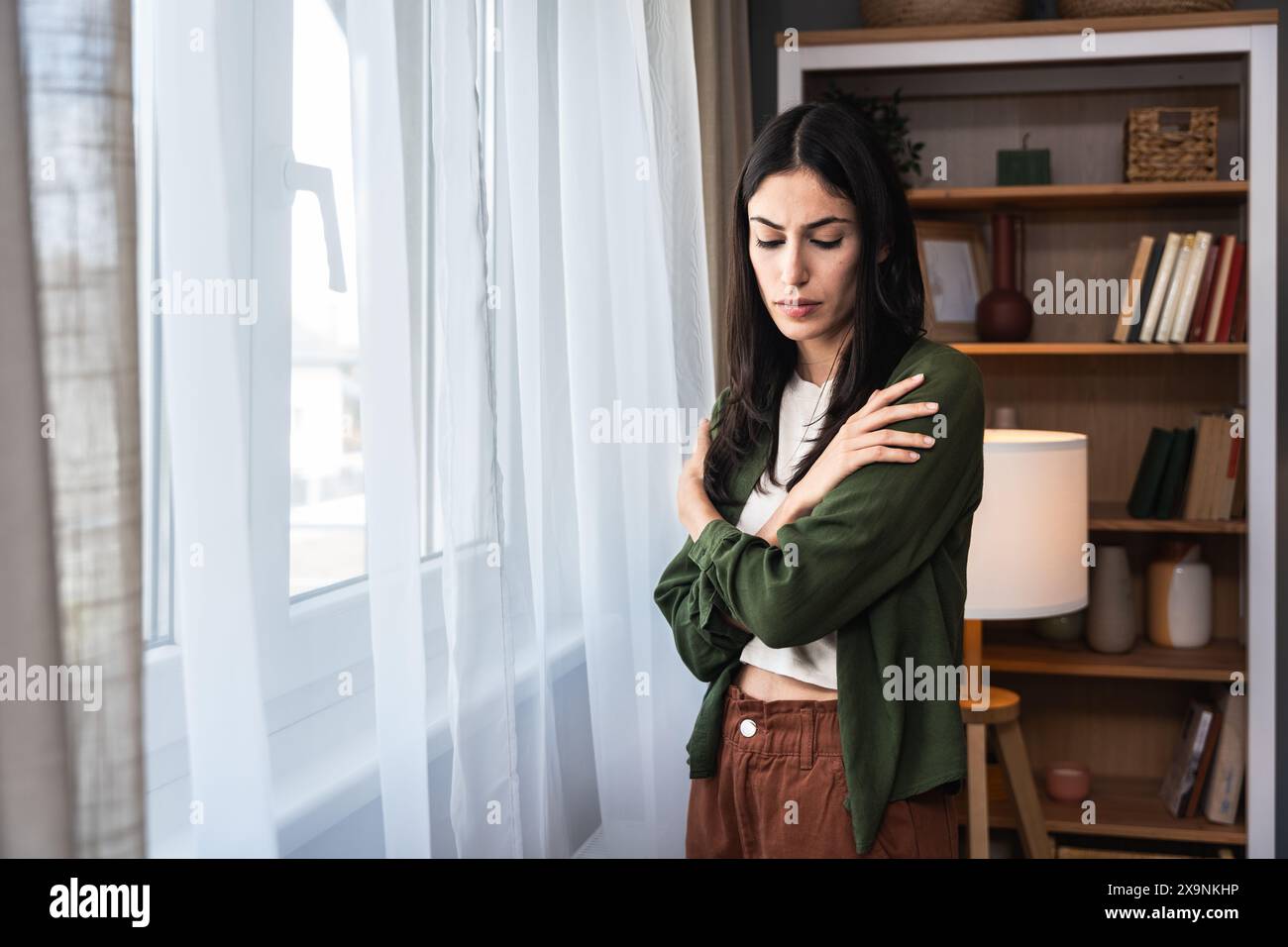 Young sad and depressed woman feeling regret and anxiety standing near ...
