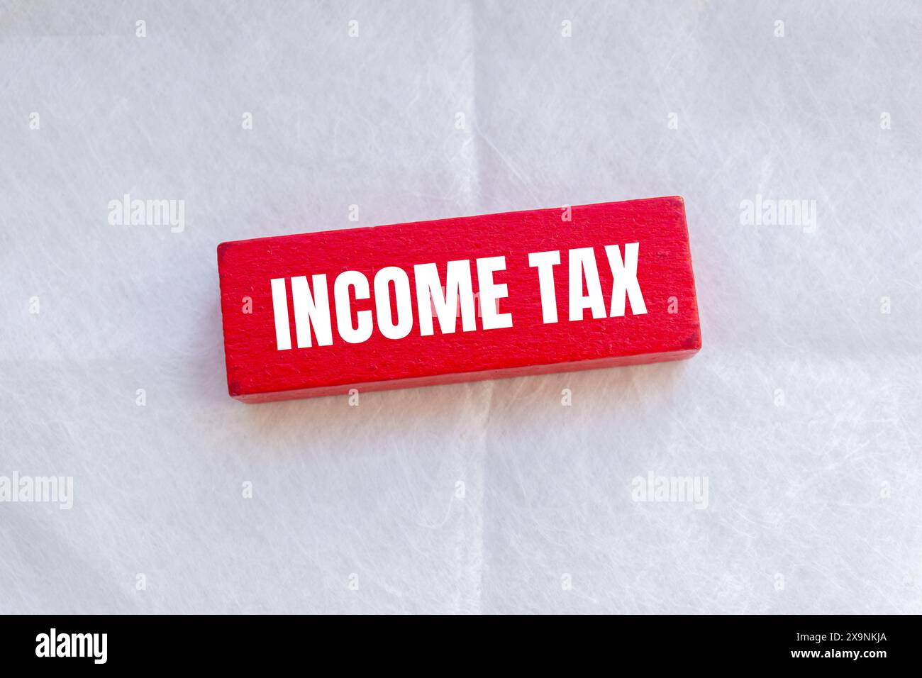 Income tax words written on red wodoen block with white background ...