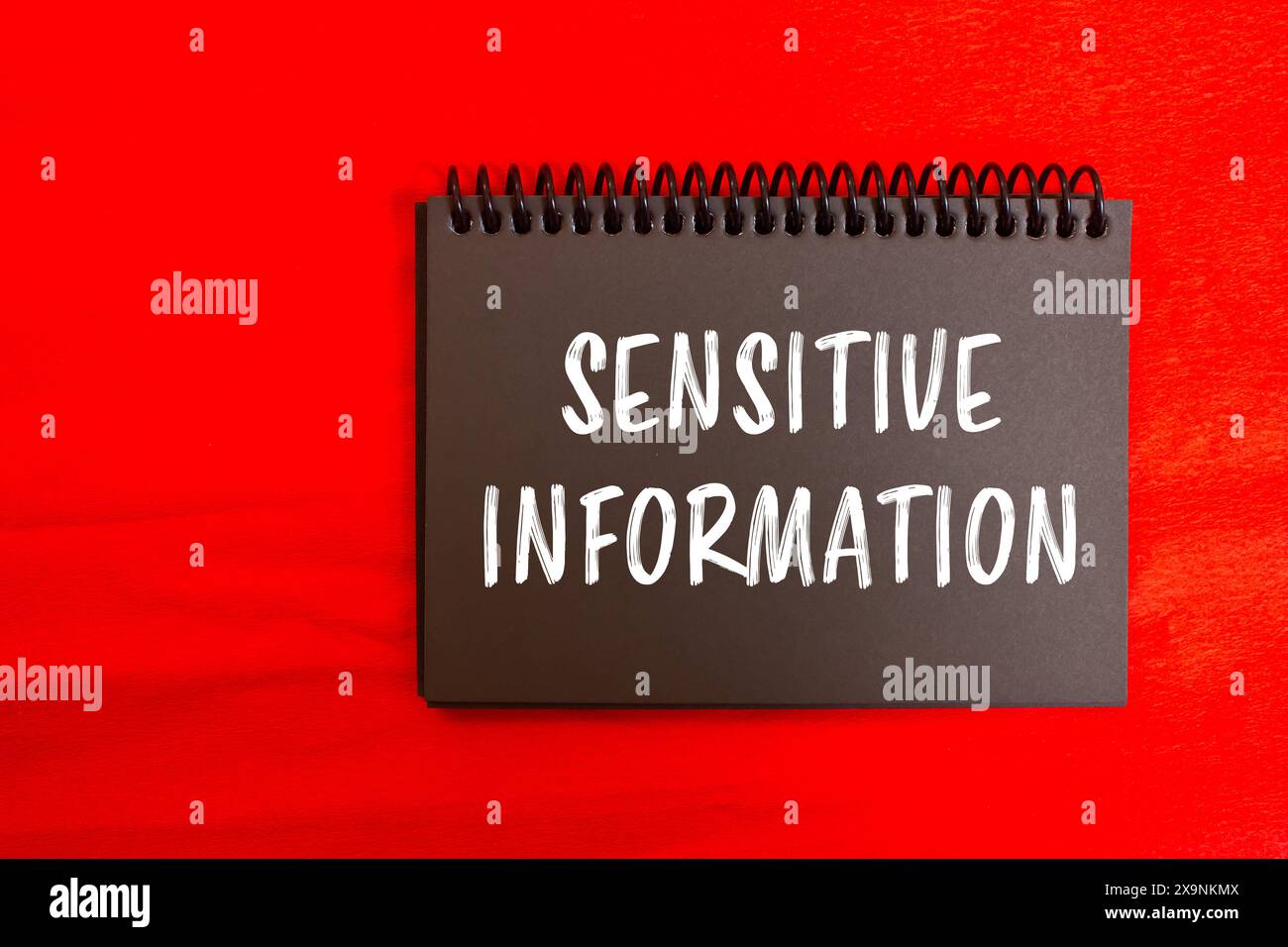 Sensitive information message written on black notebook page with red ...