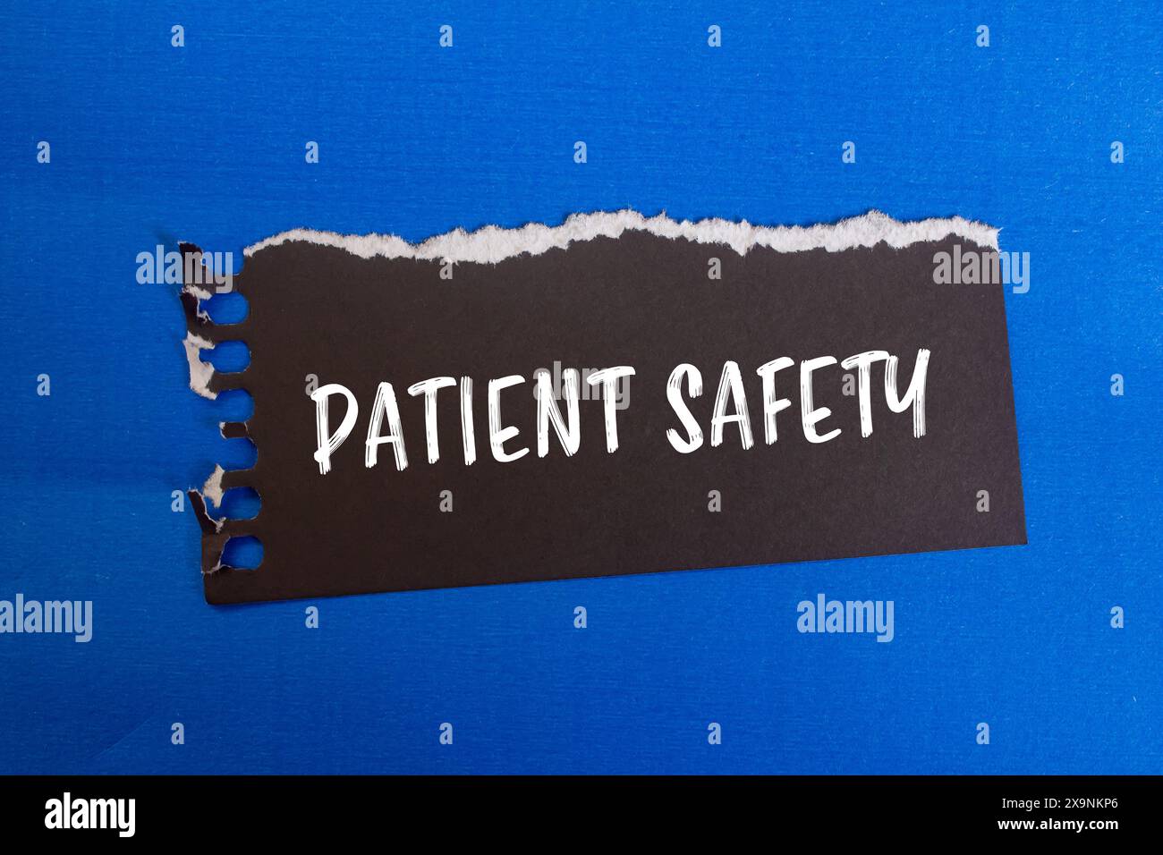 Patient safety message written on ripped black paper piece with blue ...