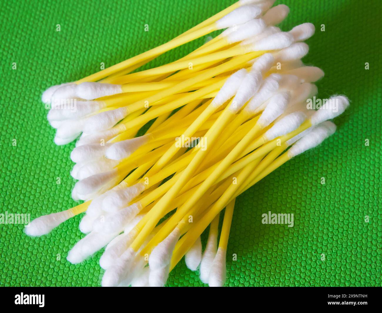 Ear Care. Yellow cotton swabs for ear cleaning, green base Stock Photo ...