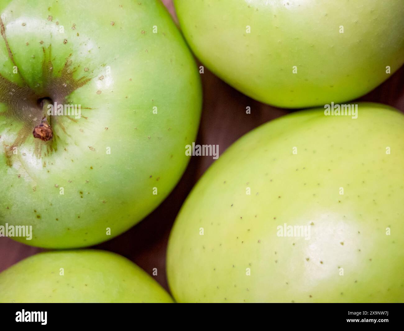 A cluster of ripe green apples, their glossy skins dotted with natural ...