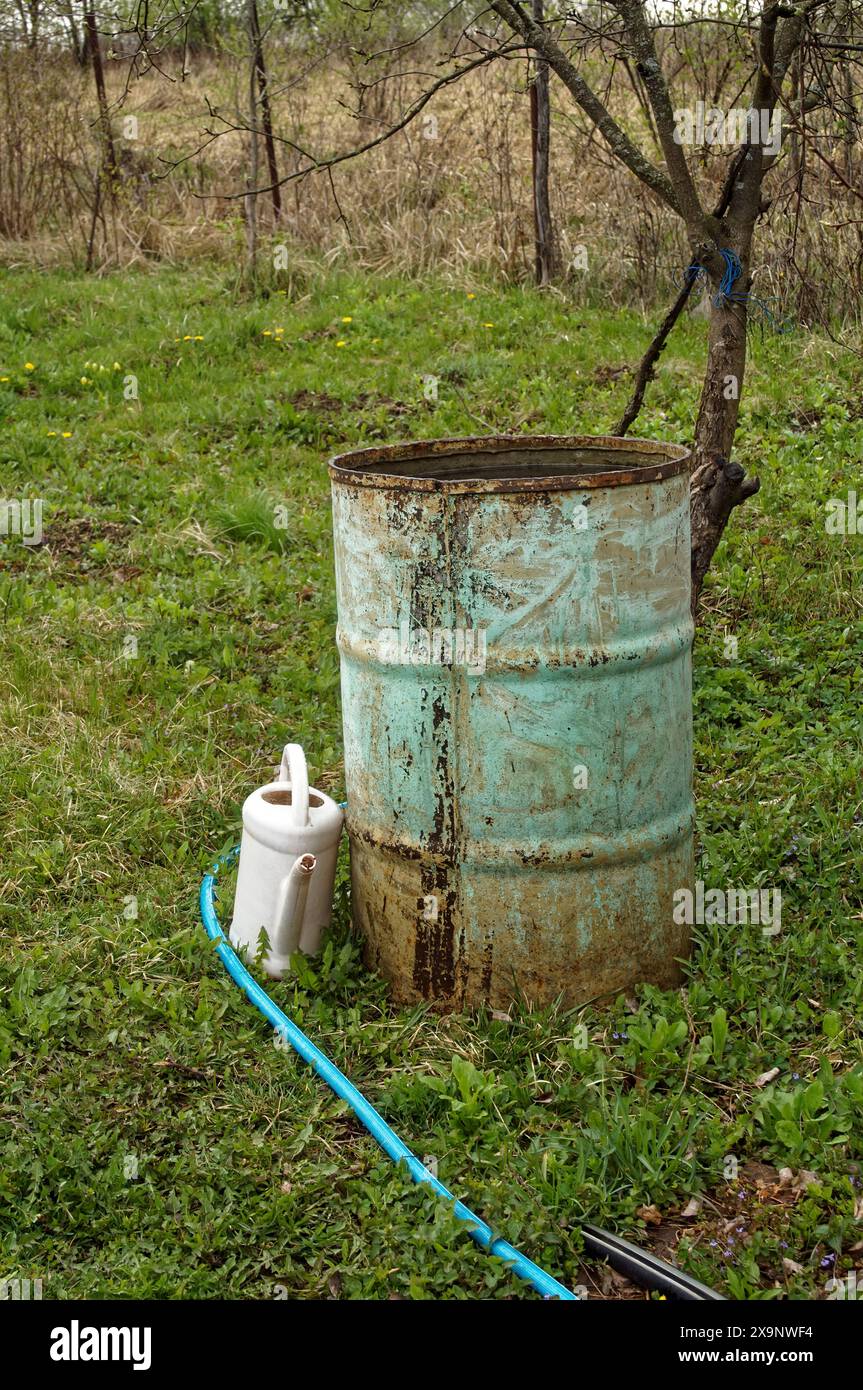 Old metal barrel with water in the garden, in spring Stock Photo - Alamy