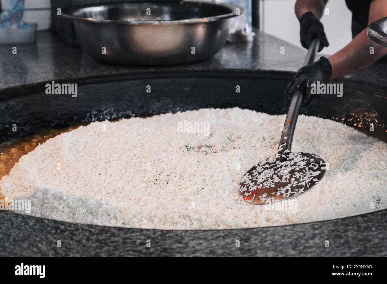 hands of a male cook cooking traditional oriental Uzbek rice pilaf in a ...