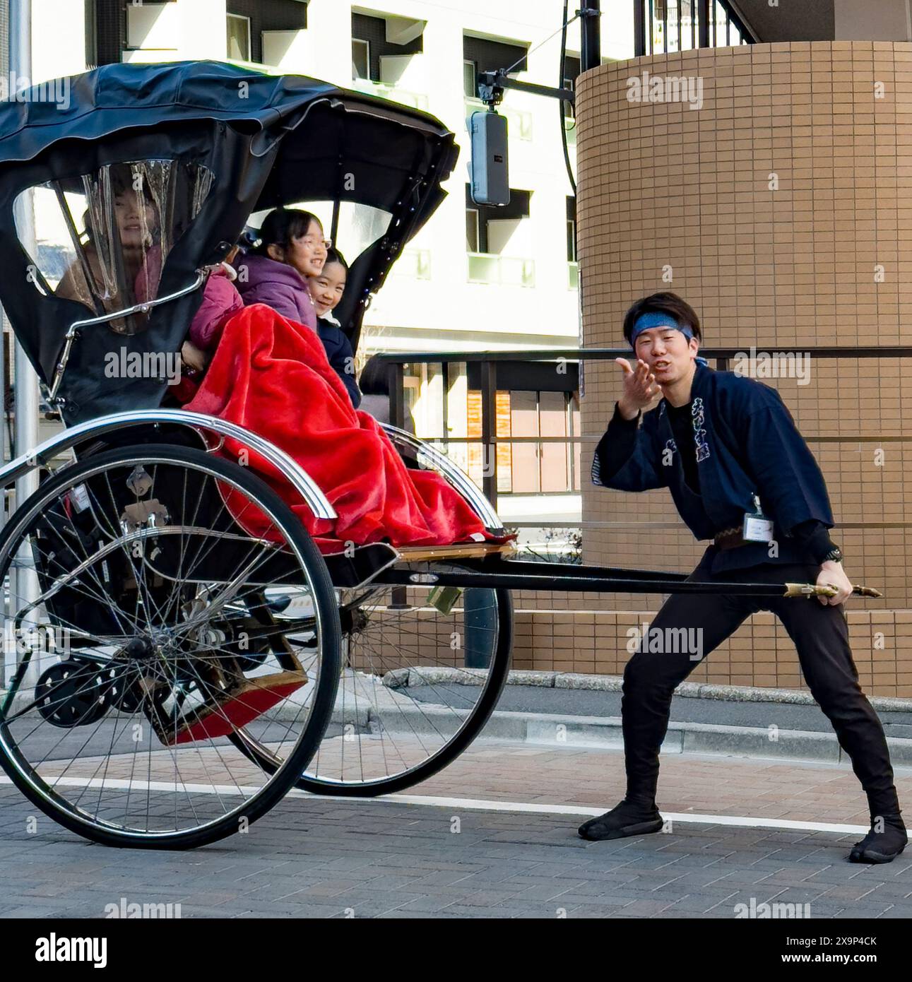 Rickshaw runner in traditional attire transports tourists through an ...