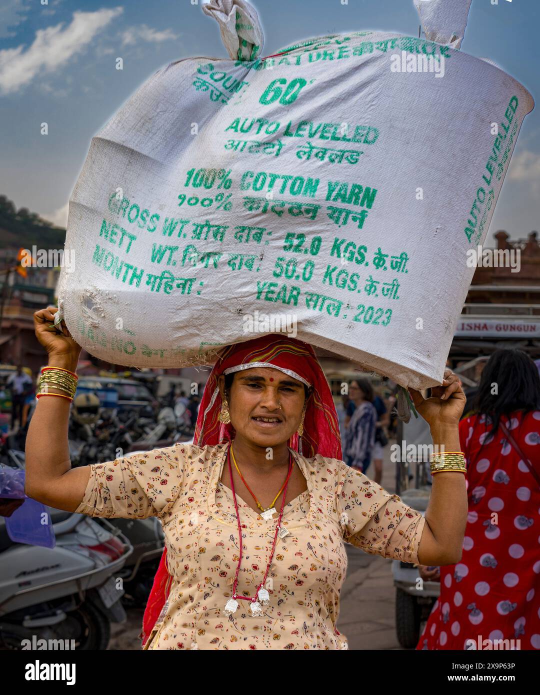 Indian woman balances a large burlap sack on her head while walking ...