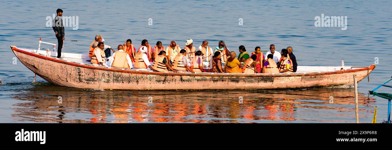 Traditional boat ferrying people across calm waters during golden hour ...