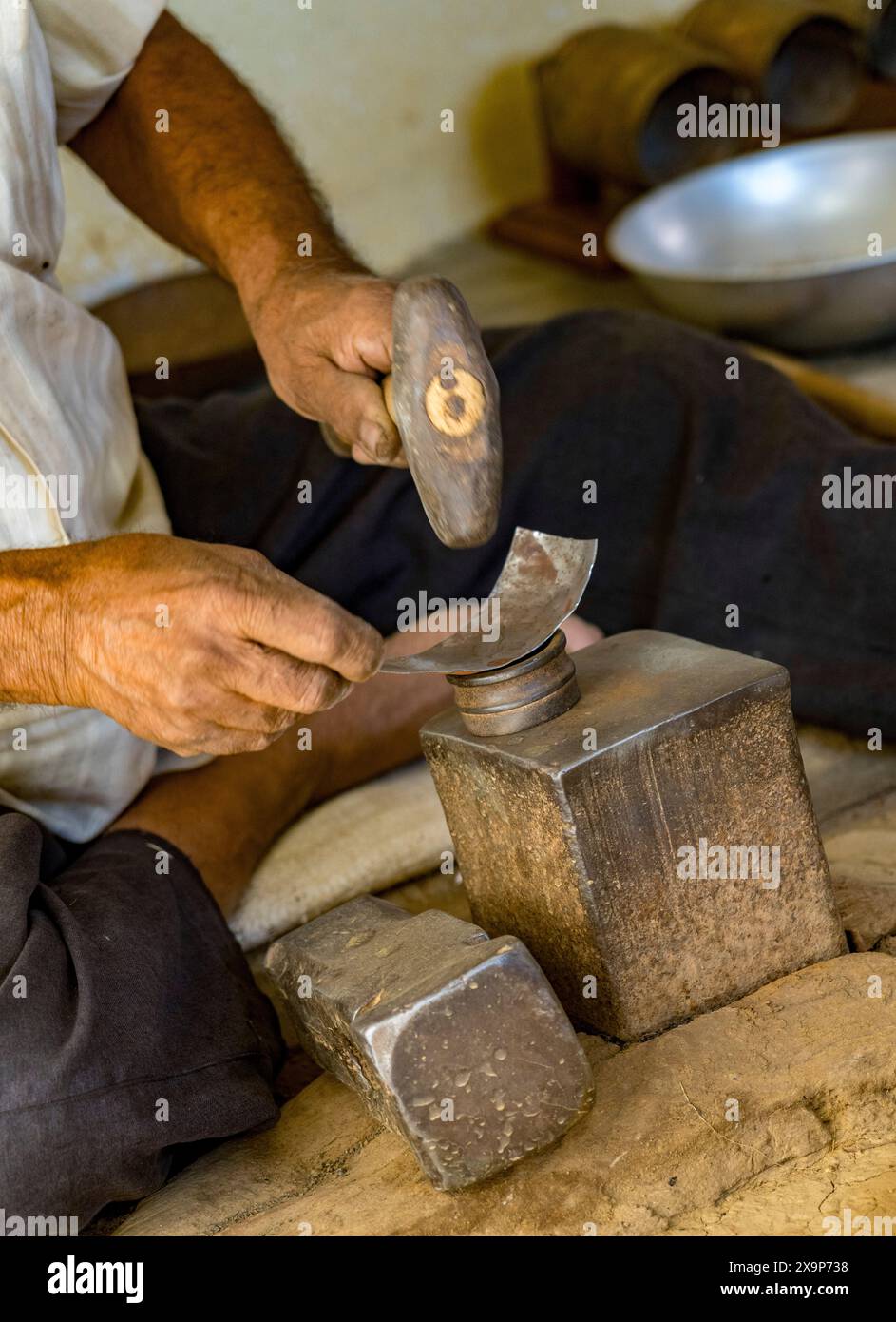 Closeup of a skilled artisan's hands sharpening a blade with a stone in ...