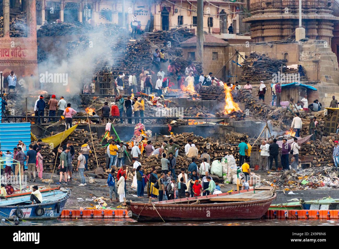 Solemn cremation ritual at a sacred river ghat, with pyres alight and ...
