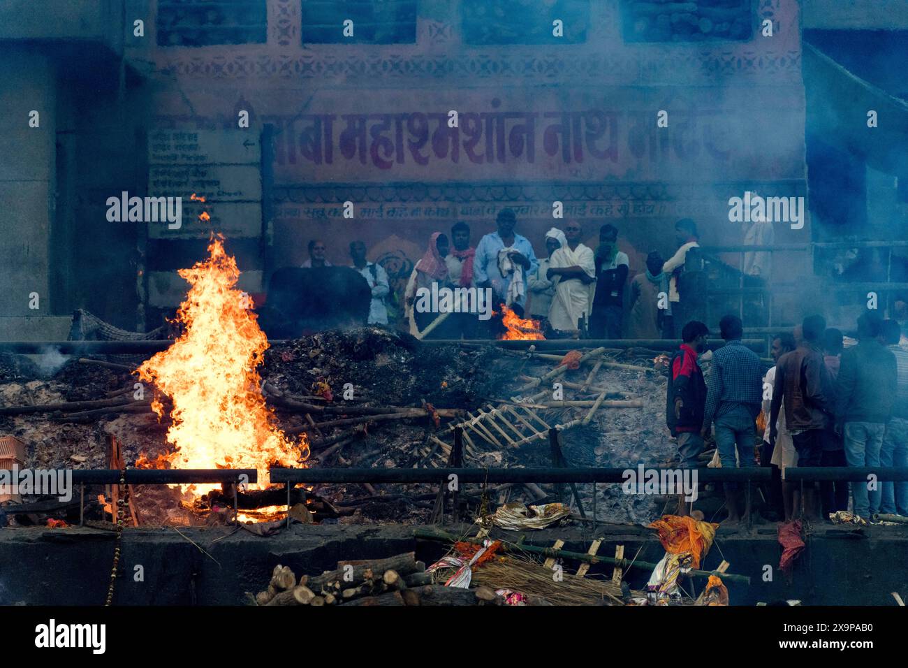 People gather at a ceremonial pyre during a traditional cremation ...