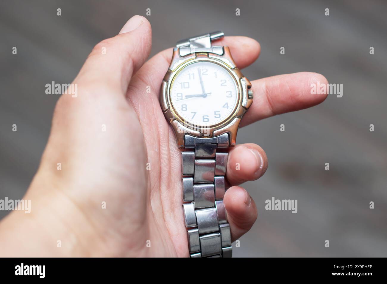 The person is wearing an analog watch on their wrist, displaying the ...