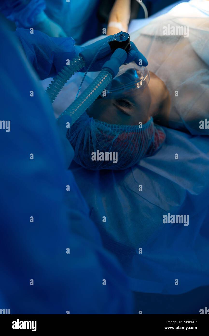 Anesthetist applying anesthesia machine to female patient in operating ...
