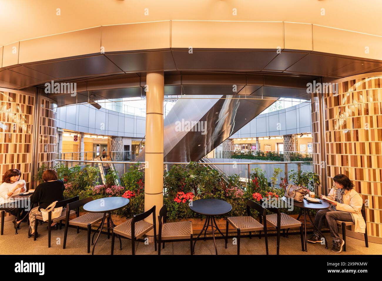 Seating and tables on a balcony overlooking the escalators with three ...