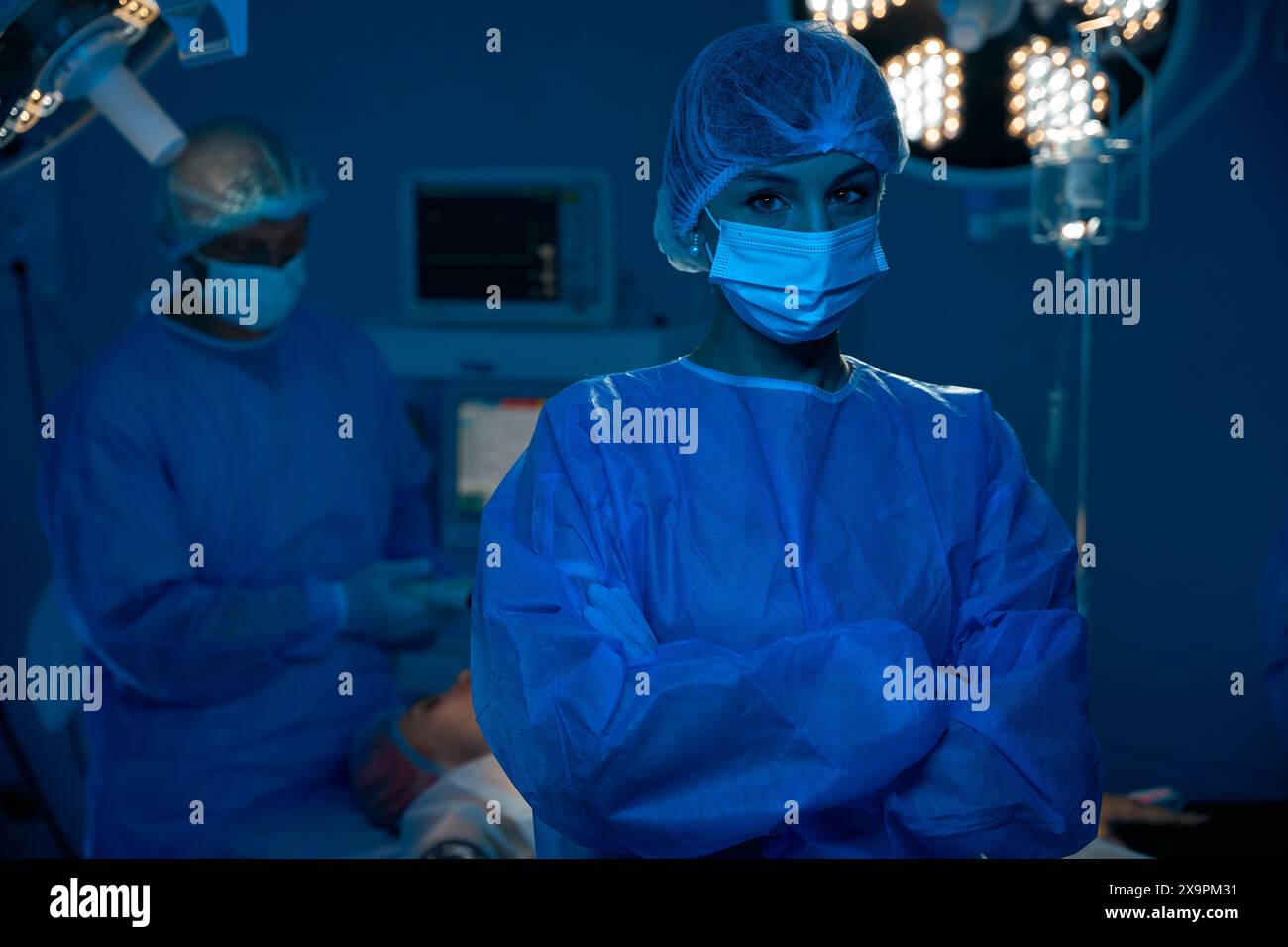 Female doctor in surgical uniforms standing in dark modern operating ...