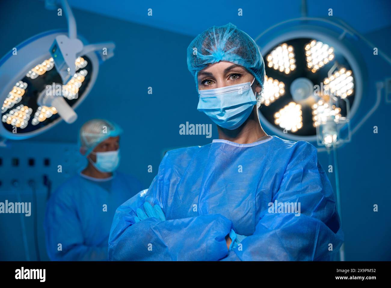 Doctor posing in operating room on background of surgeons performing ...