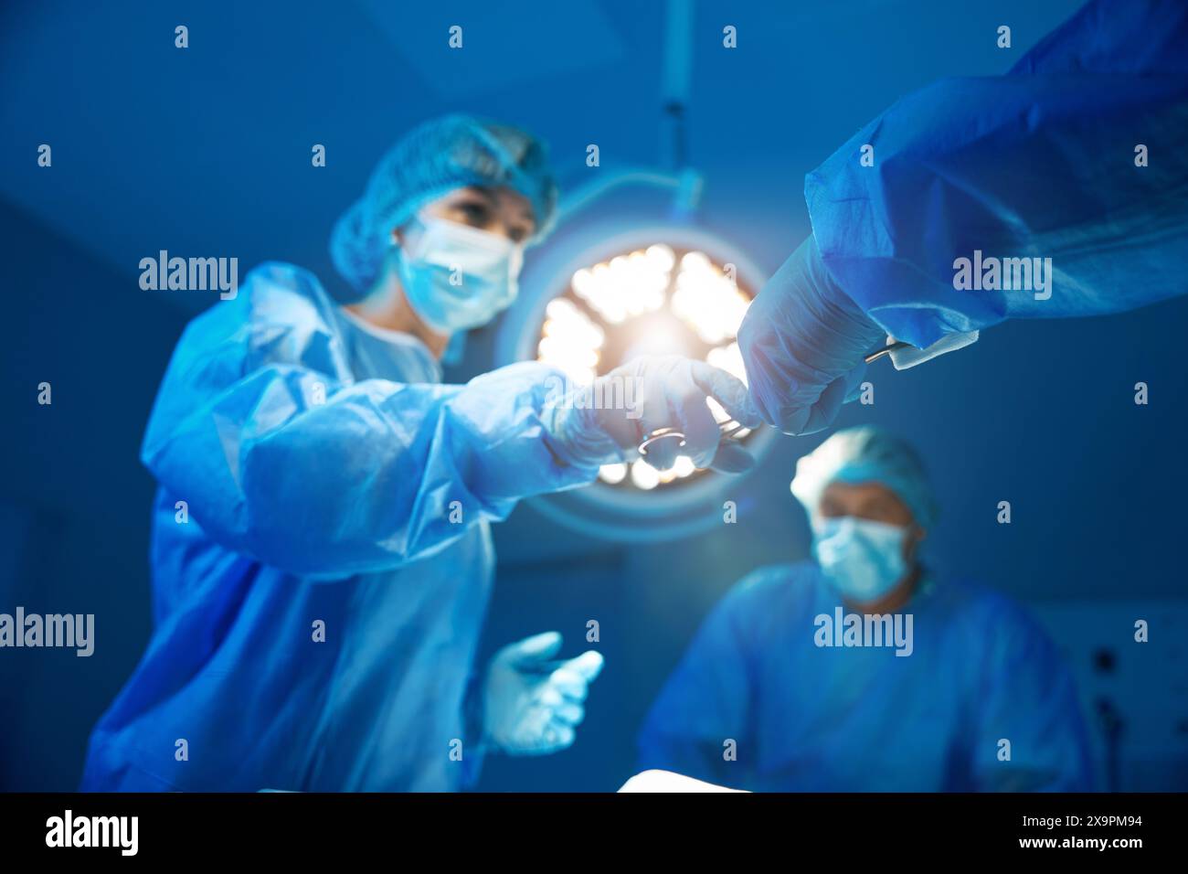 Assistant handing out instrument to surgeons during operation Stock ...