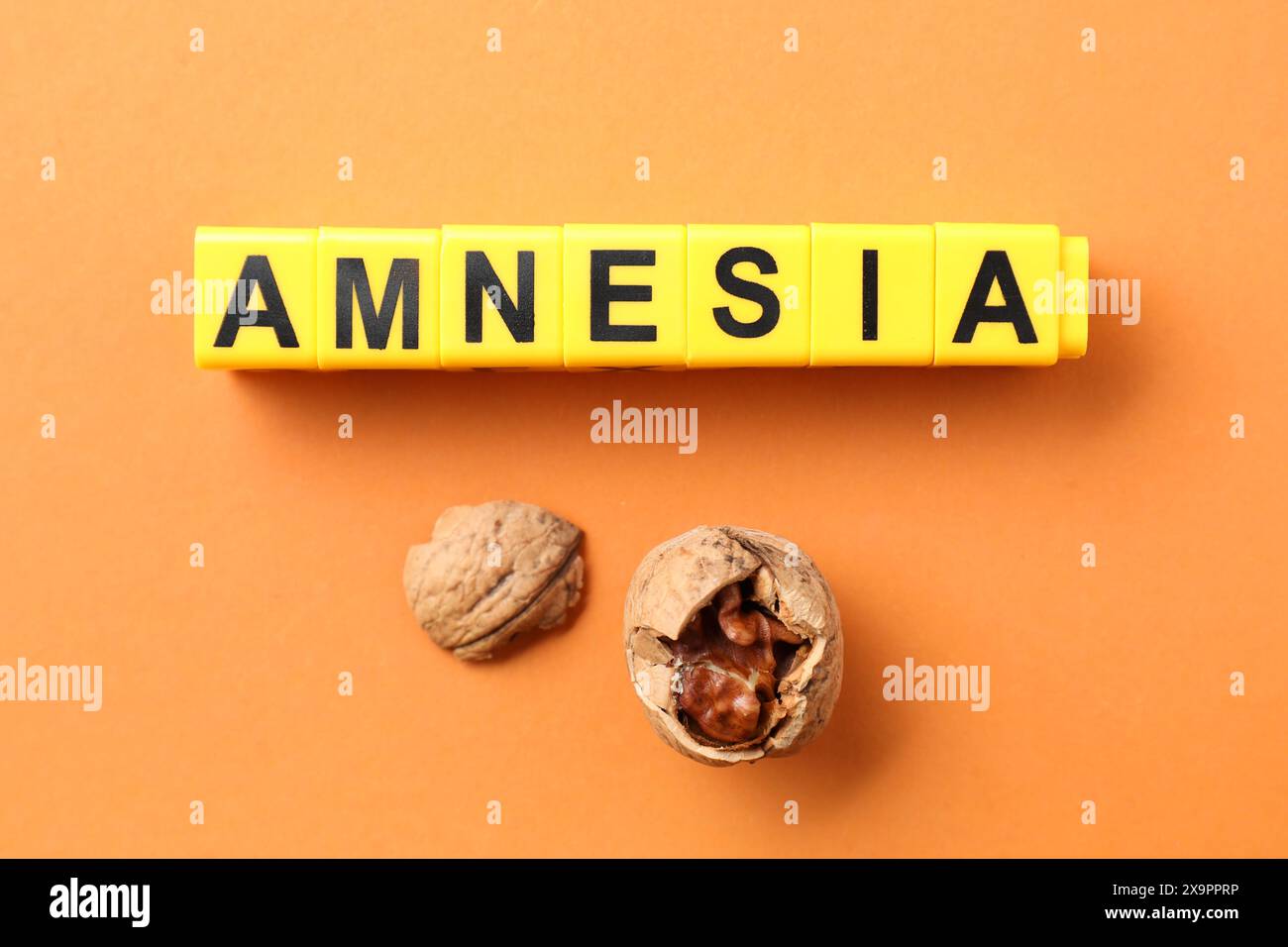 Word Amnesia made of yellow cubes and broken walnut on orange ...