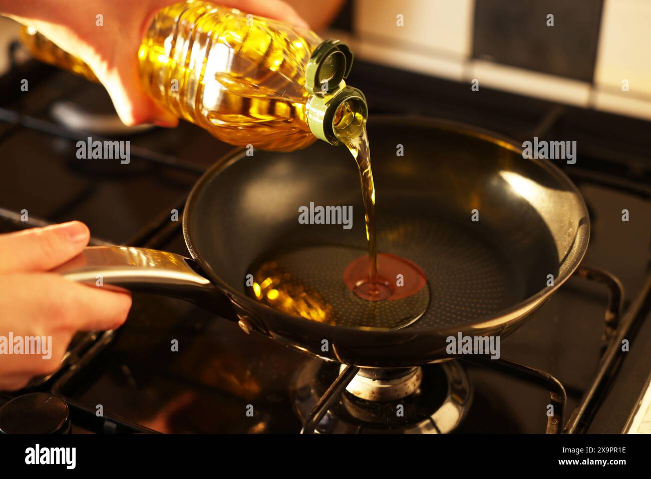 Vegetable fats. Woman pouring oil into frying pan on stove, closeup ...