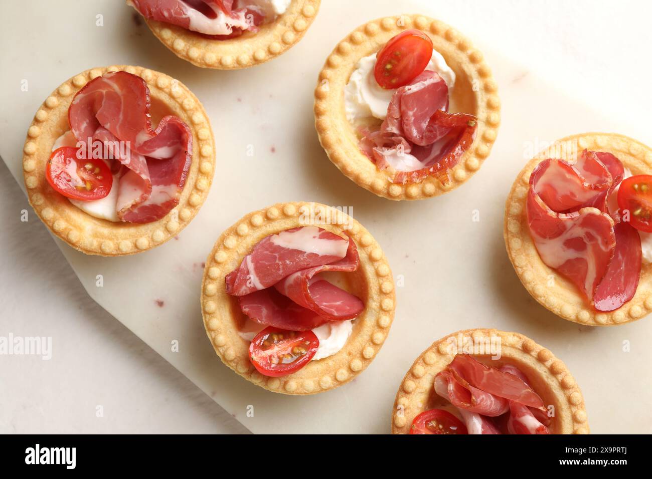 Delicious canapes with jamon, cream cheese and cherry tomatoes on white ...