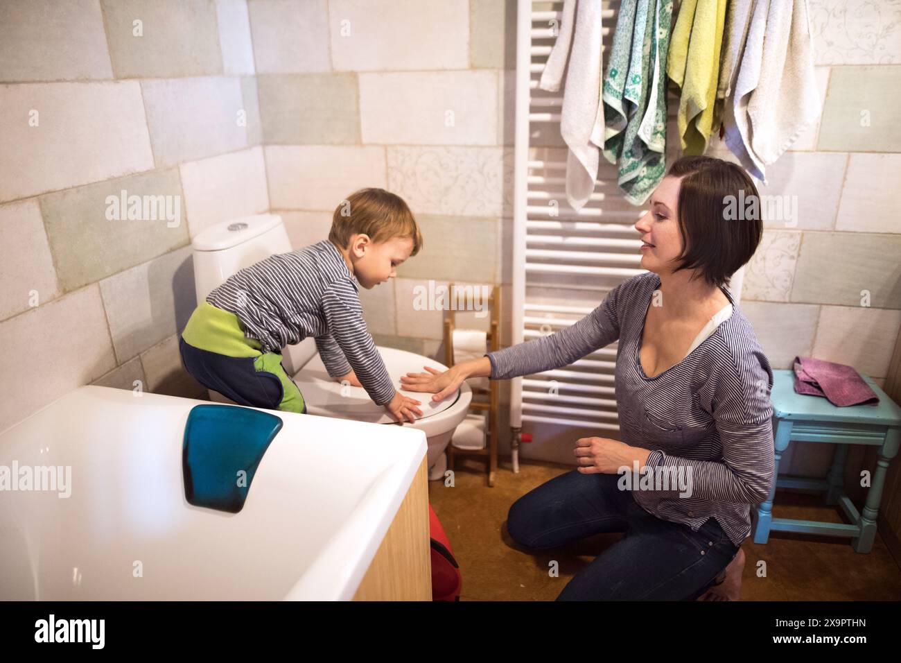 Mom is helping toddler boy use the toilet. Potty-trained little boy in ...