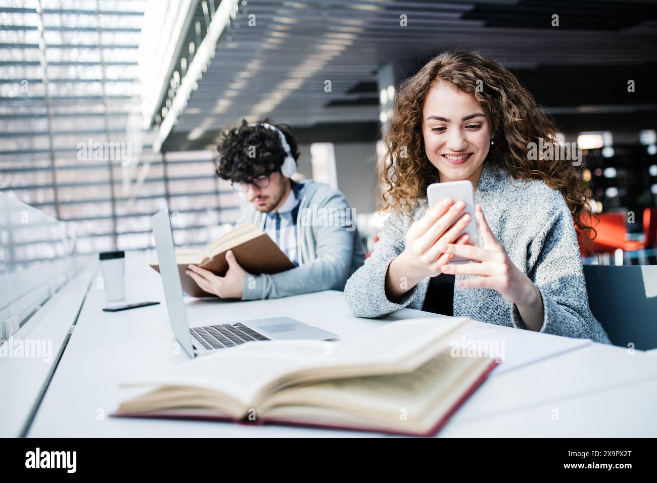 Young female student in library, focusing on final project ...
