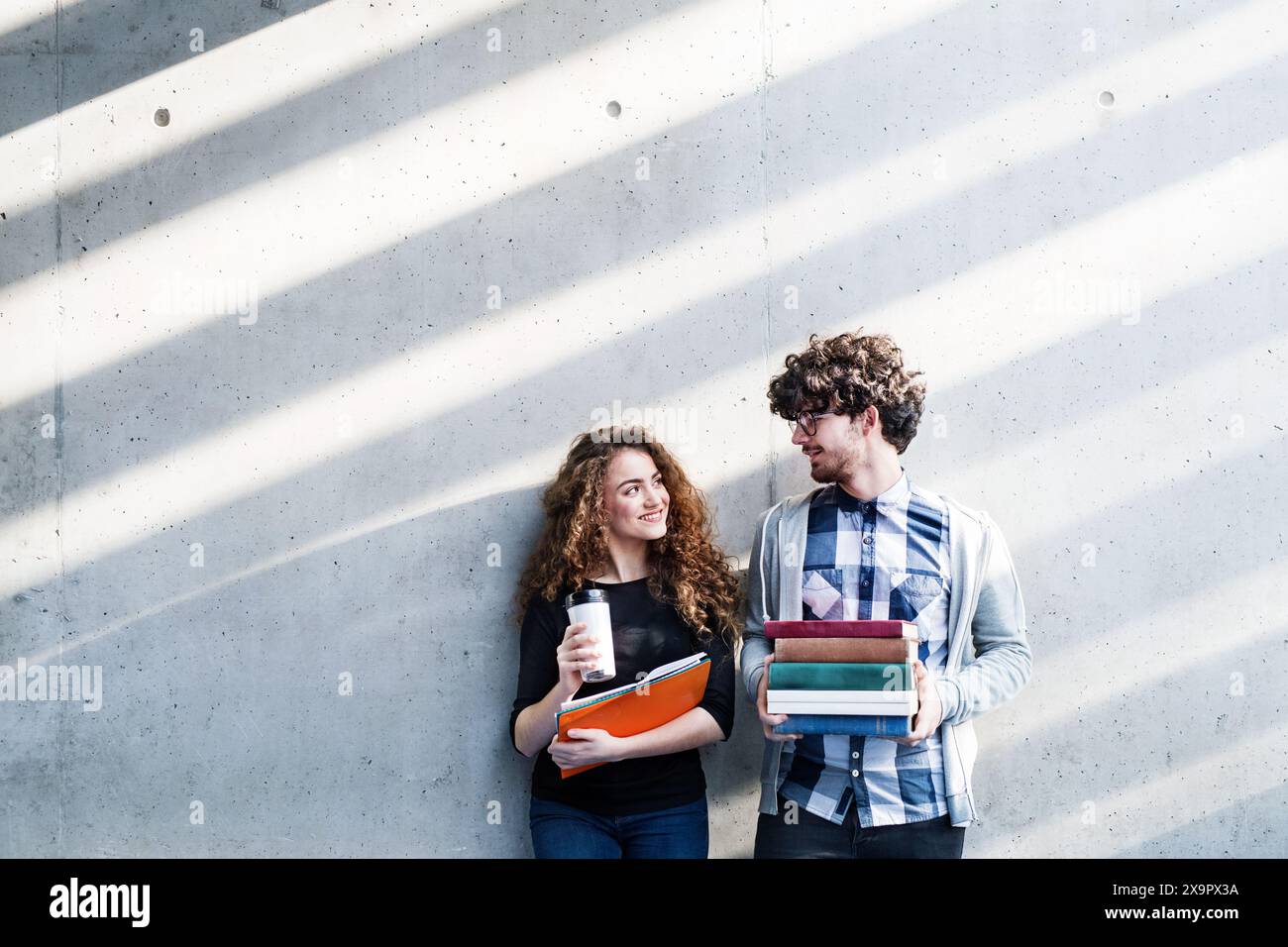 Young university students, holding stack of books, preparing for final ...