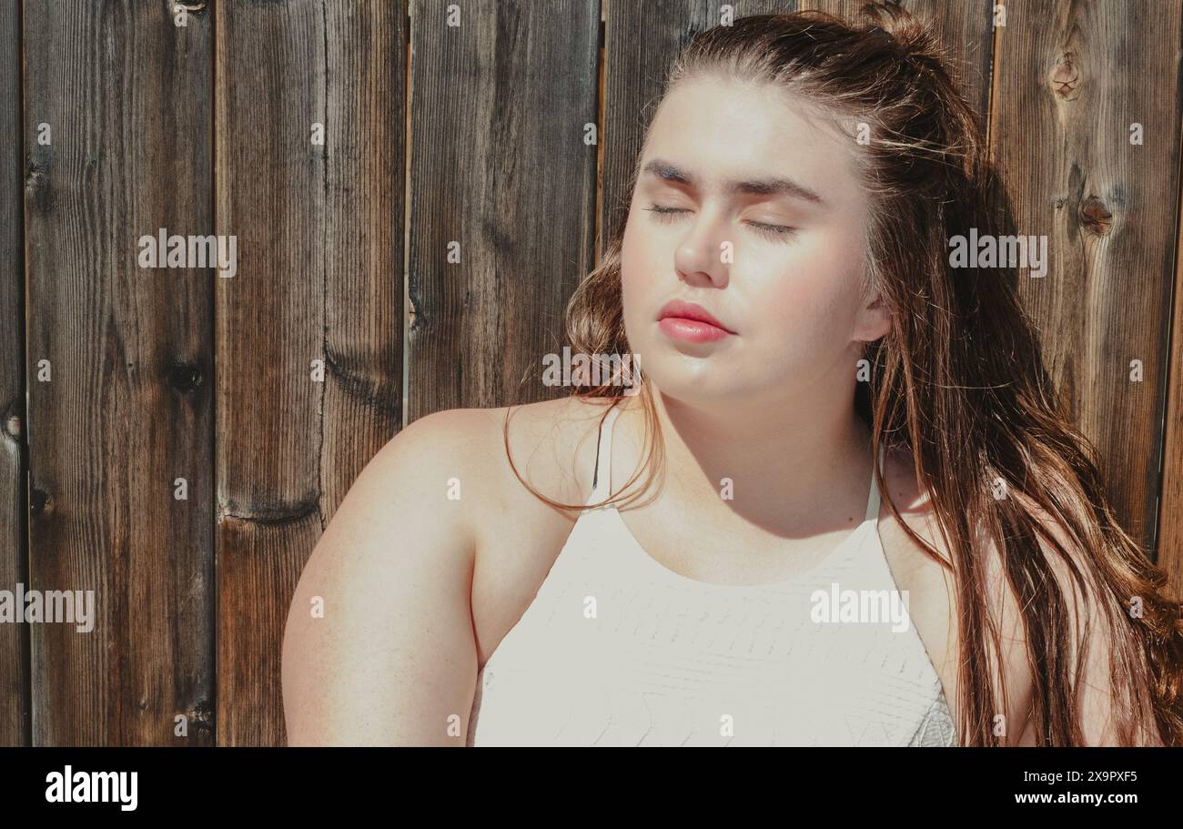 Young woman basking in the sunlight. Wooden background Stock Photo - Alamy