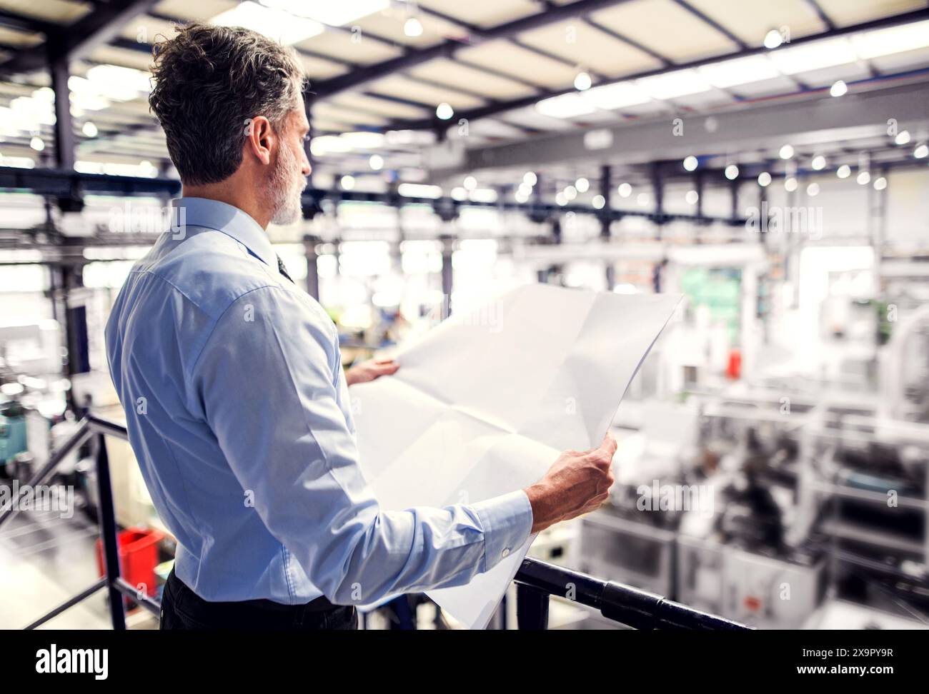 Portrait of project manager reading blueprint modern industrial factory ...
