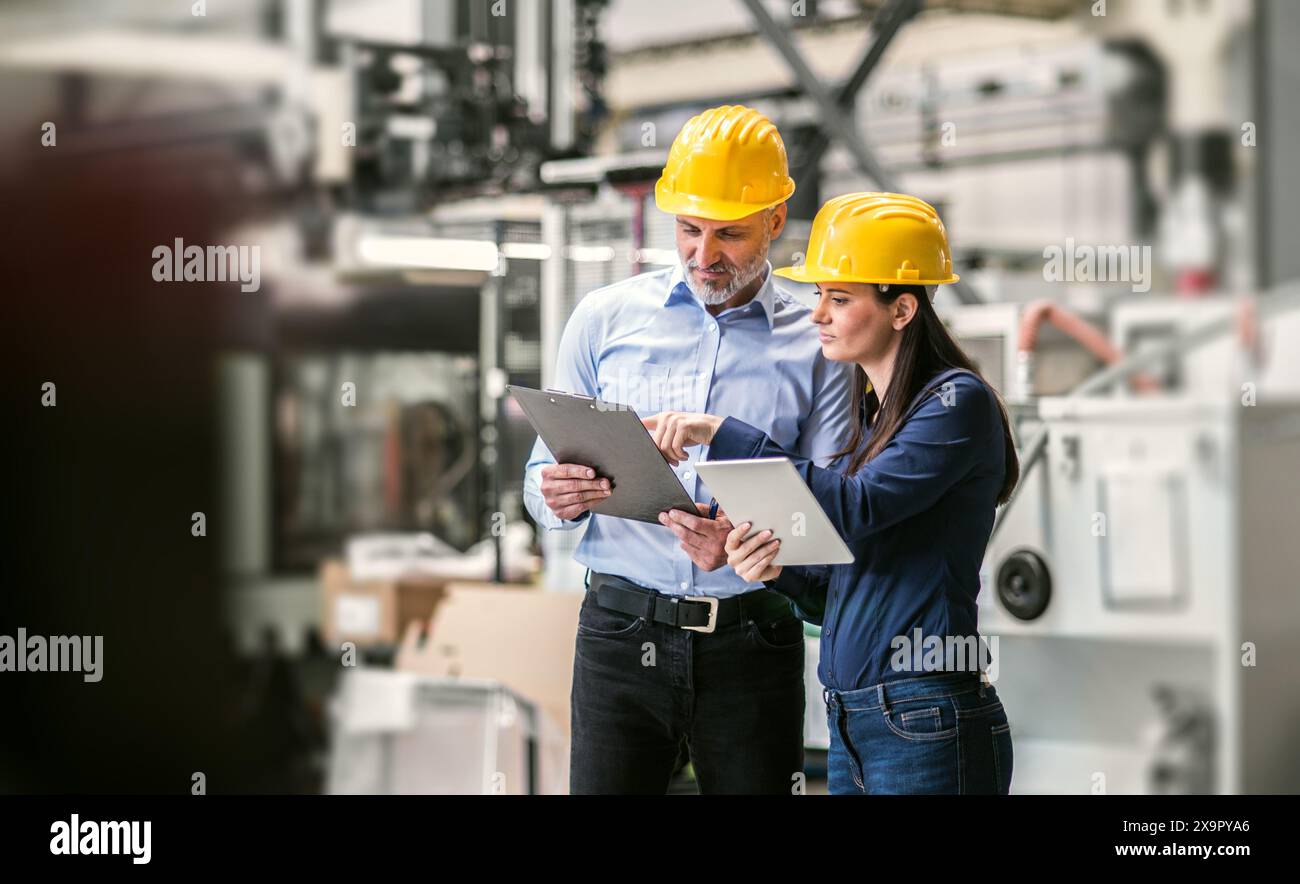 Two project managers standing in modern industrial factory ...