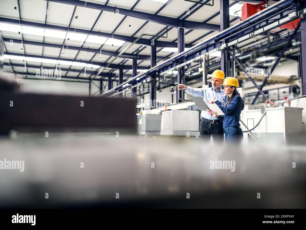 Two project managers standing in modern industrial factory ...