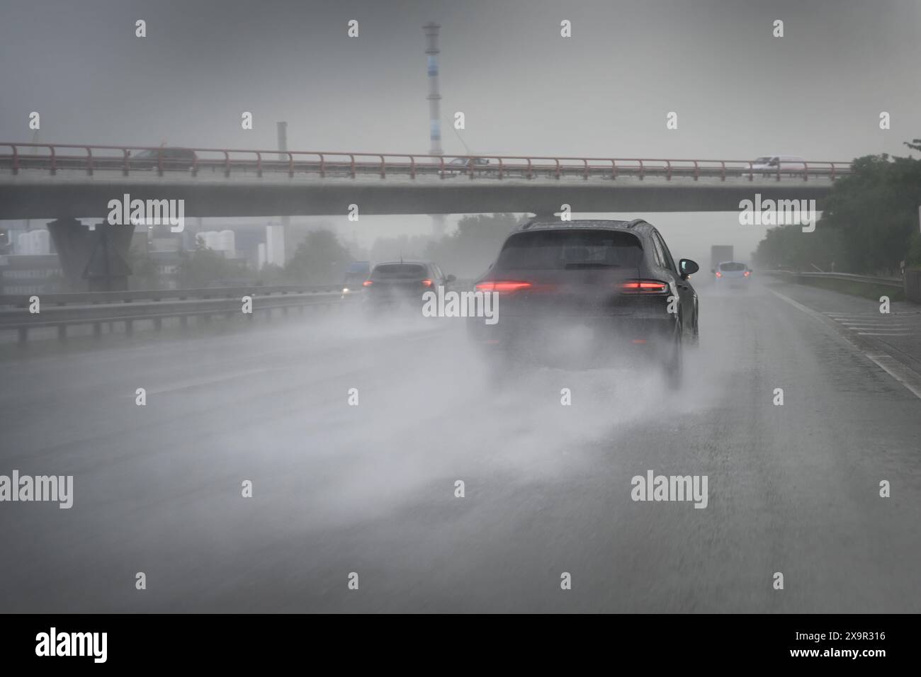 Cars driving too fast in heavy rain on wet roads with poor visibility ...